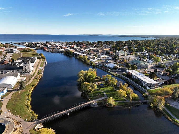 Alpena's Thunder Bay River wraps around town like a warm embrace, autumn colors reflected perfectly in water so still it looks painted.