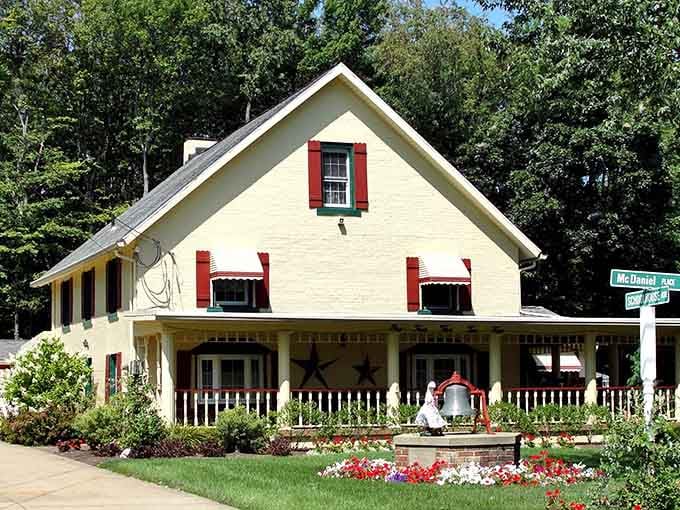 This cheerful yellow farmhouse with red shutters looks like it belongs on a greeting card, honestly.