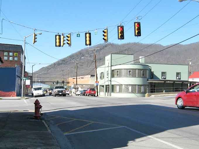 Big Stone Gap's art deco corner building stands cool and confident beneath a crisp, mountain-framed blue sky.