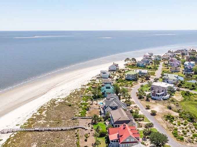 Bird's-eye view reveals colorful beach houses dotting the shore like a pastel rainbow someone spilled on purpose.