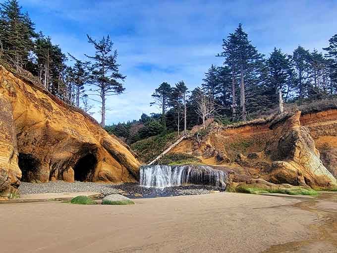 A waterfall spilling onto golden sand beside carved sea caves is Hug Point's way of saying, "You're welcome, everyone."