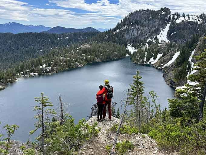 Two hikers standing together on a rocky ledge above Rampart Lakes, sharing a view that no photograph can fully capture.