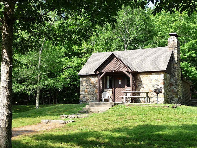 This charming stone cabin tucked beneath a canopy of green trees is rustic comfort done absolutely right.