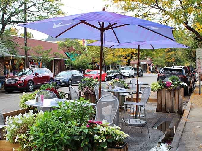 Flower boxes and purple umbrellas frame Saugatuck's irresistible sidewalk patio, where autumn leaves drift down like nature's own dinner invitation.
