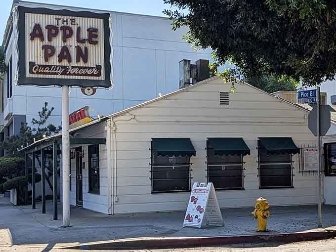 The Apple Pan's modest white cottage and "Quality Forever" sign quietly promise something the flashiest restaurants in LA simply cannot deliver.