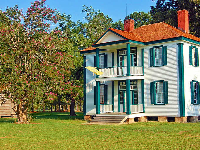 Warm afternoon light catches the teal shutters and blooming crape myrtle, giving this historic battlefield home an almost painterly glow.