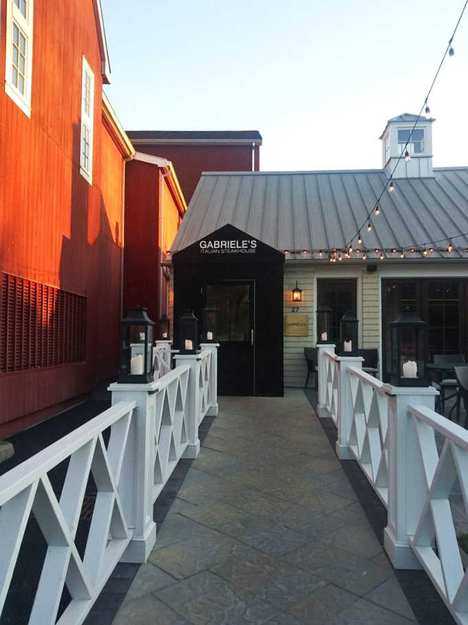 That candlelit white-fence pathway leading to a sleek black entrance door is pure Westport sophistication at its finest.