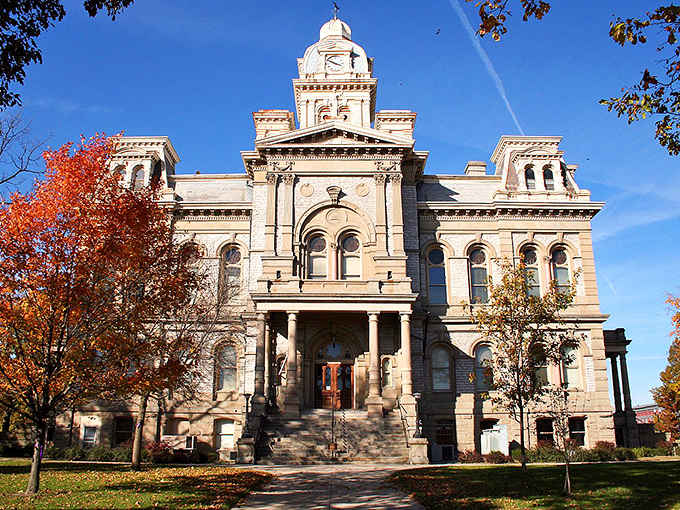 The Hancock County Courthouse rises above Sidney's busy main street like a stone-carved reminder that small towns built things to last.