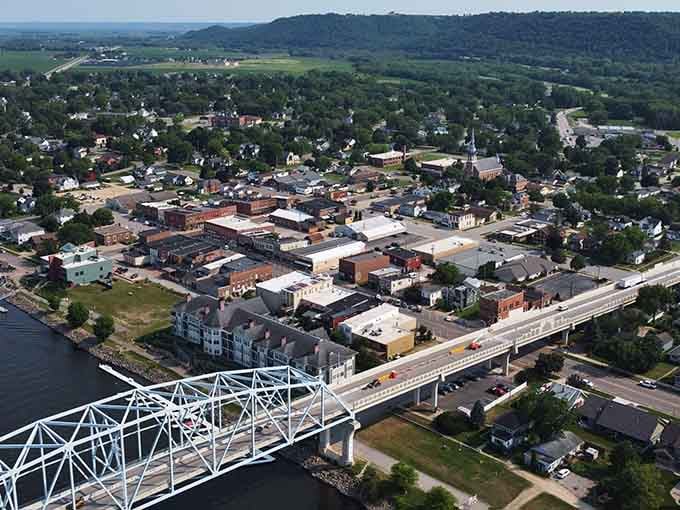 The Mississippi River bridge connects communities while that church steeple reaches skyward with timeless grace.