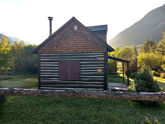Golden hour catches the cedar shingles of this cabin just right, the mountain ridge glowing like something out of a dream.