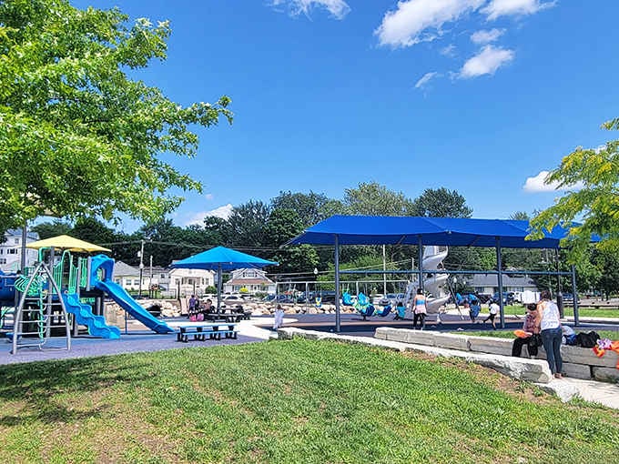Blue canopies shade happy families at play, creating summer memories that'll last longer than any smartphone photo ever could.