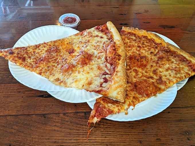 A cheese slice so massive it requires architectural support from the plate beneath it.