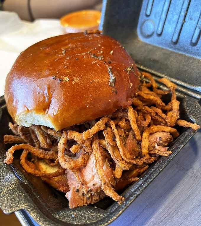 Smoked meat piled onto a brioche bun with crispy Haystack onions spilling out everywhere, gloriously.