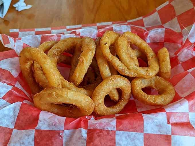 Golden, crispy, and piled high in a red-checked basket. These onion rings are the supporting cast that steals the whole show.