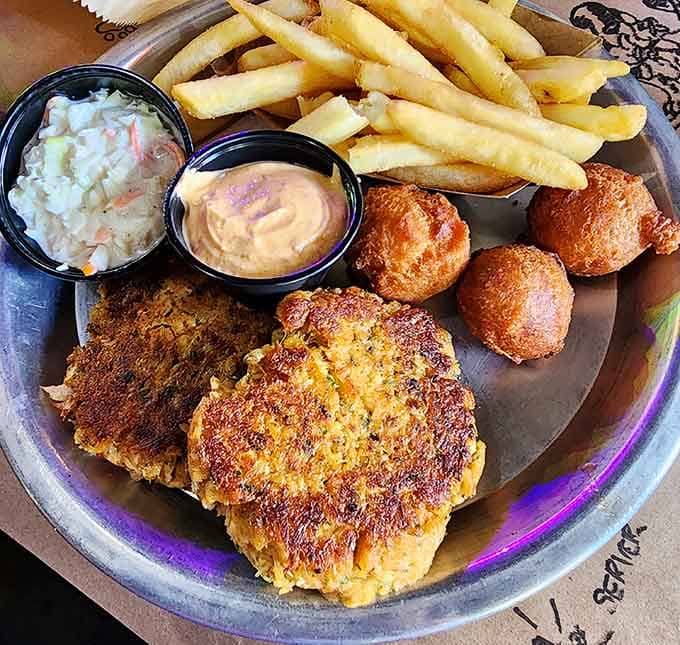 Two golden crab cakes, a pile of fries, and hushpuppies. This plate is not playing around with your emotions.