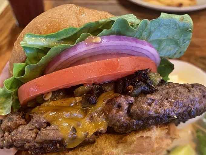 A burger stacked with caramelized onions, melted cheese, tomato, and lettuce. This beauty means absolutely no-nonsense business.