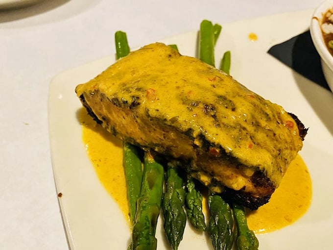 Blackened salmon resting on fresh asparagus, draped in a vibrant sauce that demands your full attention.
