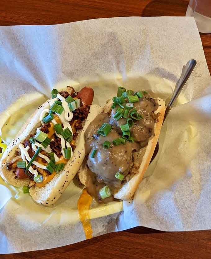 Two dogs side by side, one saucy and loaded, one smothered in gravy, both absolutely magnificent.