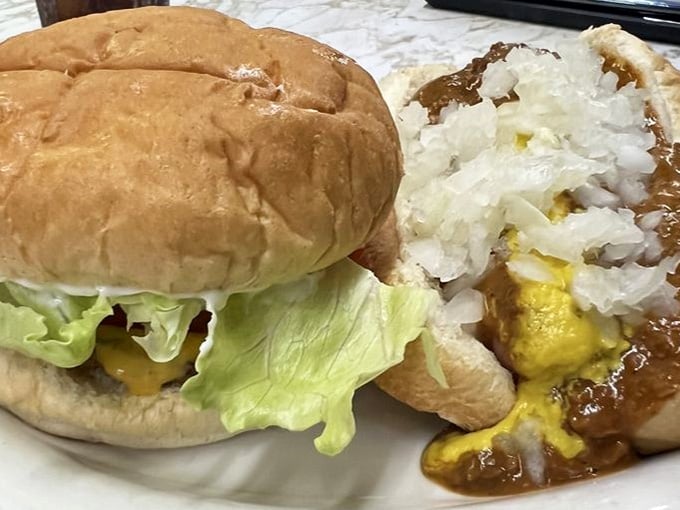 A cheeseburger and a coney dog sharing a plate, because sometimes the best decision is simply ordering both.
