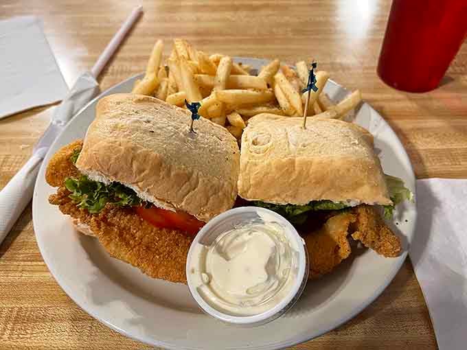 That catfish po'boy, golden and crispy, arrives with fries and tartar sauce like it already knows it's the star.