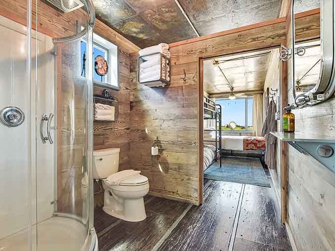 Reclaimed wood walls, a glass shower, and fresh towels stacked neatly. Who knew a shipping container bathroom could feel this good?