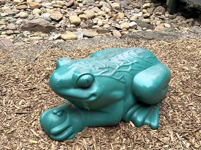 This cheerful teal frog sitting in the wood chips is the park's unofficial mascot, and honestly, he's earned it.