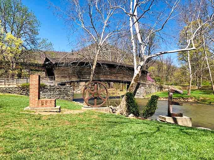 A rusty mill wheel stands beside the arching bridge like a proud old neighbor who's seen absolutely everything and has no complaints.