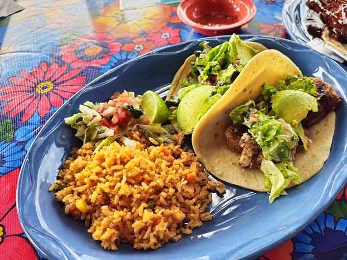 Tacos with rice, pico, and guacamole on a floral tablecloth, this is what a good afternoon looks like.