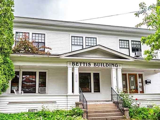 The Bettis Building wears its white clapboard dignity like a well-pressed shirt on a Sunday morning.