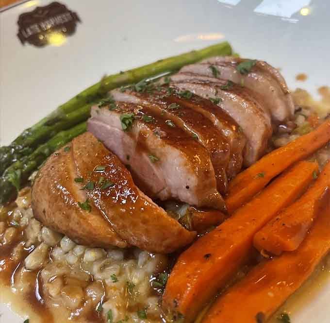 Sliced duck breast over what appears to be a grain base, flanked by asparagus and glazed carrots. Absolutely stunning.