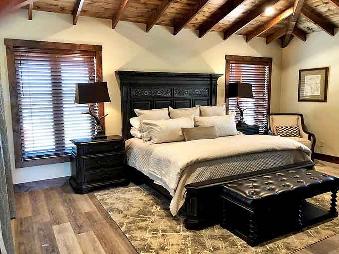 Dark wood furniture, crisp linens, and exposed beam ceilings make this bedroom the kind of place you genuinely never want to leave.