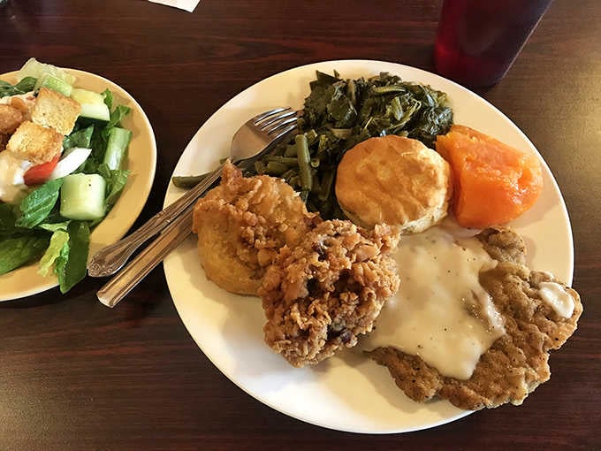 Fried chicken, collard greens, yams, and a golden biscuit, proof that a great Southern plate needs absolutely nothing else.