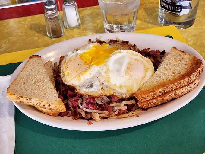 Corned beef hash topped with two sunny-side-up eggs and toast on the side, breakfast doesn't get more honest than this.