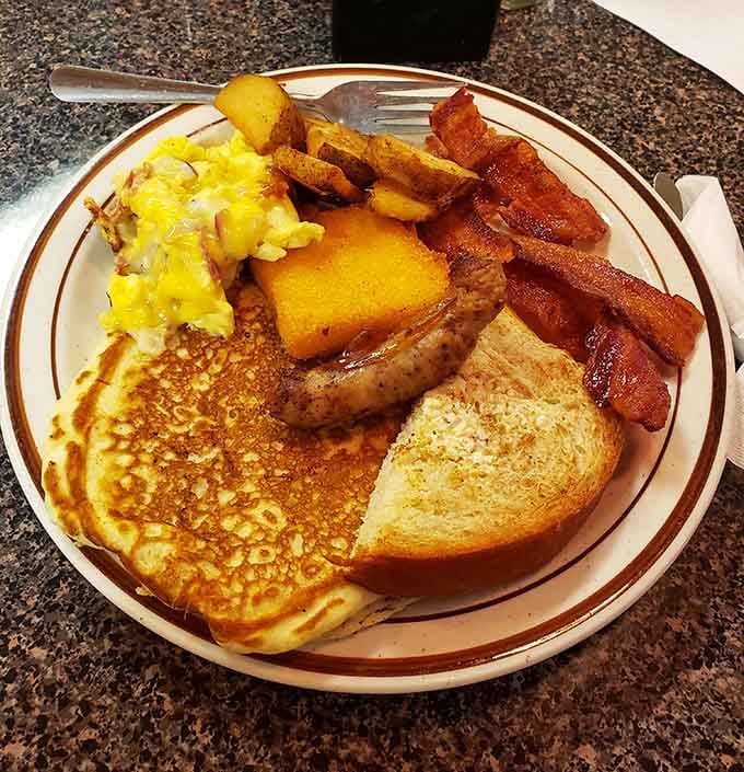 Pancakes, bacon, eggs, sausage, and home fries on one plate. Breakfast here means business.