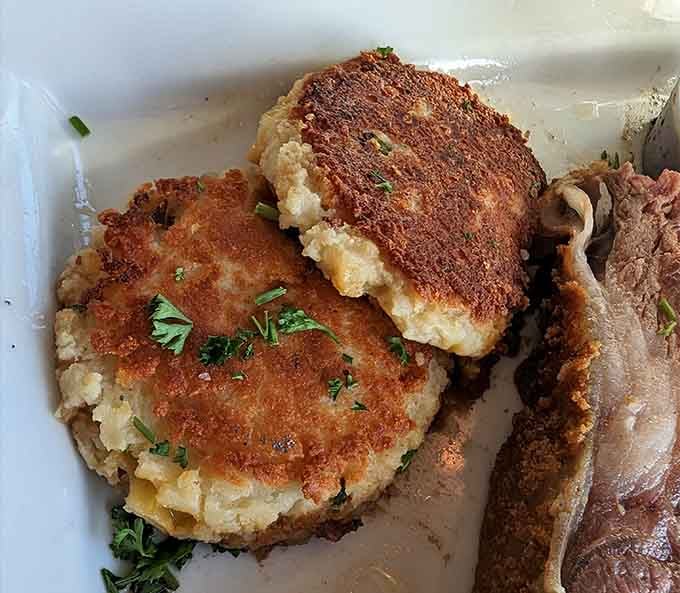 Two beautifully golden pan-seared potato cakes with a crispy crust and herb-flecked interior, the kind of side dish that quietly steals the whole show.