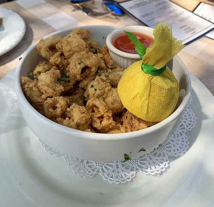 Golden fried calamari served with a lemon wrapped in mesh netting, because even the garnish here has good manners.