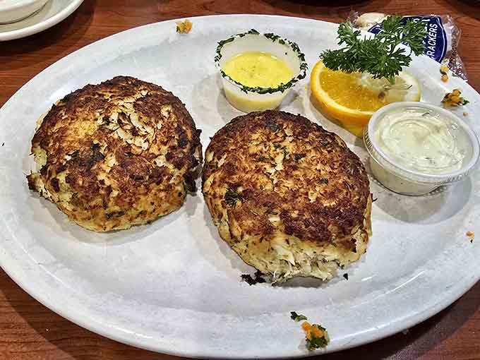 Two beautifully bronzed crab cakes sitting proud on a plate, with tartar sauce and lemon ready for their close-up.