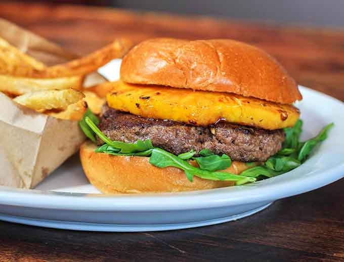 A grilled pineapple slice sitting proudly on a beef patty, sweet meets savory in the most unexpected way.