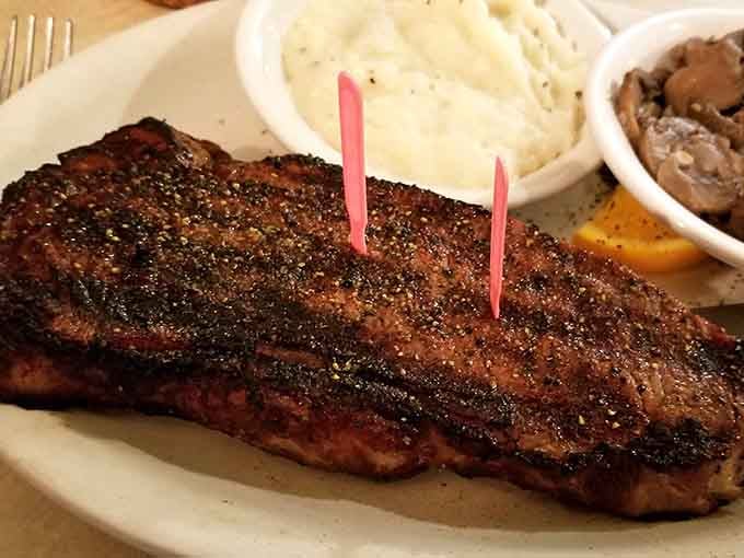 A perfectly grilled strip steak with mashed potatoes and mushrooms on the side. Simple, honest, and absolutely unforgettable.
