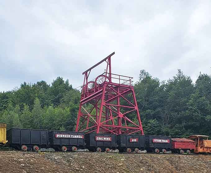 A bold red headframe towers over a row of coal cars, standing tall like a proud industrial monument to hard-working hands.
