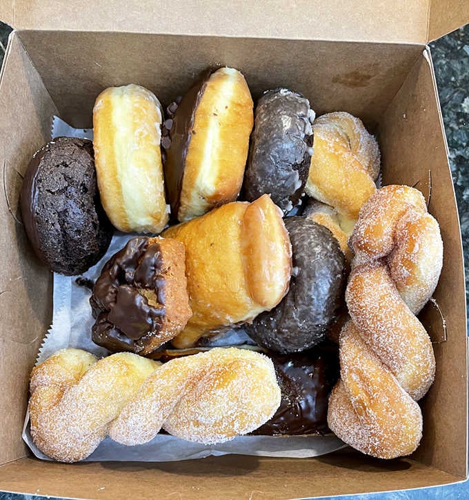 A cardboard box filled with glazed, chocolate, and cinnamon-sugar varieties proves that variety truly is the spice of breakfast life.