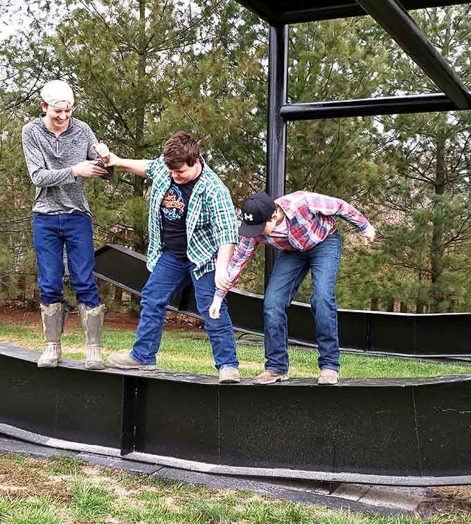 Three visitors balance on the curved rocker base, discovering that even the chair's feet are bigger than they are.