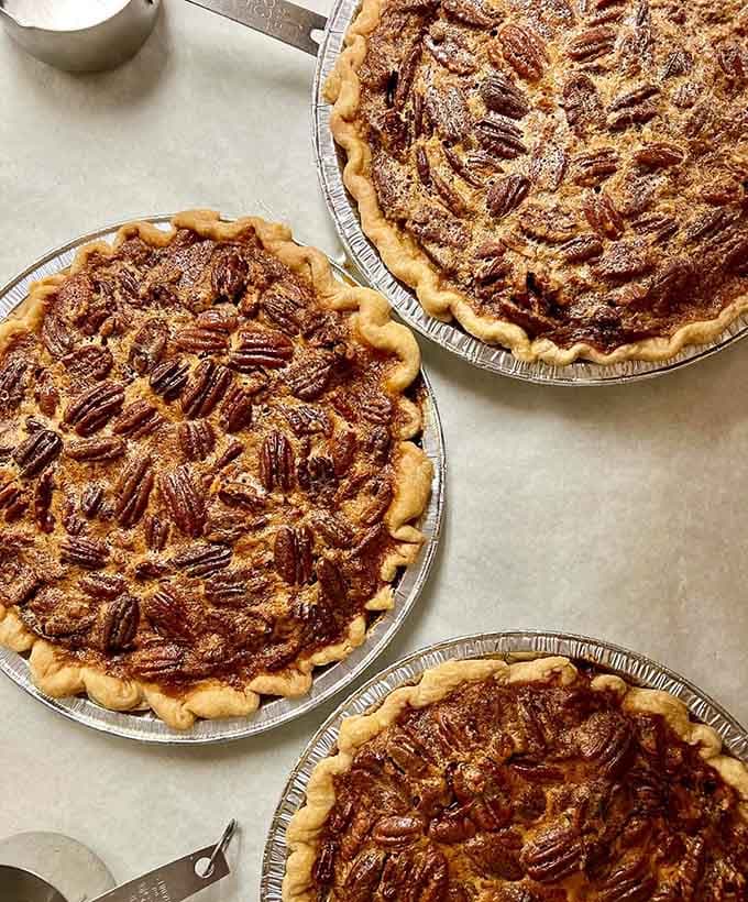 Three pecan pies sitting together like old friends, golden, rich, and completely unapologetic about how good they look.