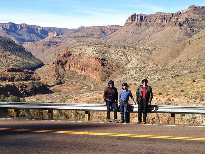 Three travelers pause to appreciate what millions of years of geology created, smartphones capturing what memories will treasure forever.