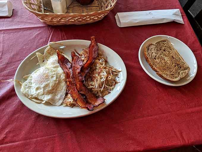 Crispy bacon, sunny-side eggs, golden hashbrowns, and toast on the side. A breakfast plate that means serious business.