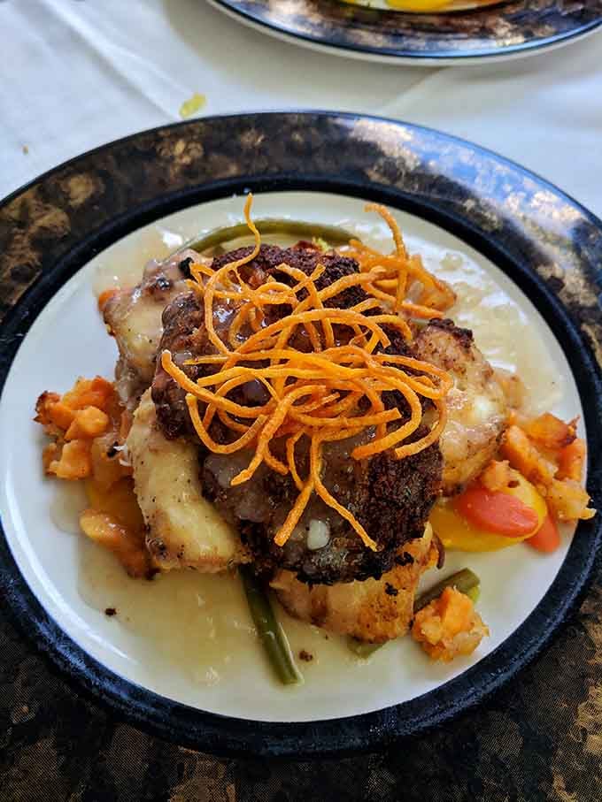 Crab-encrusted grouper sitting over creamy sauce and vegetables, a dish that earns its place on any table.