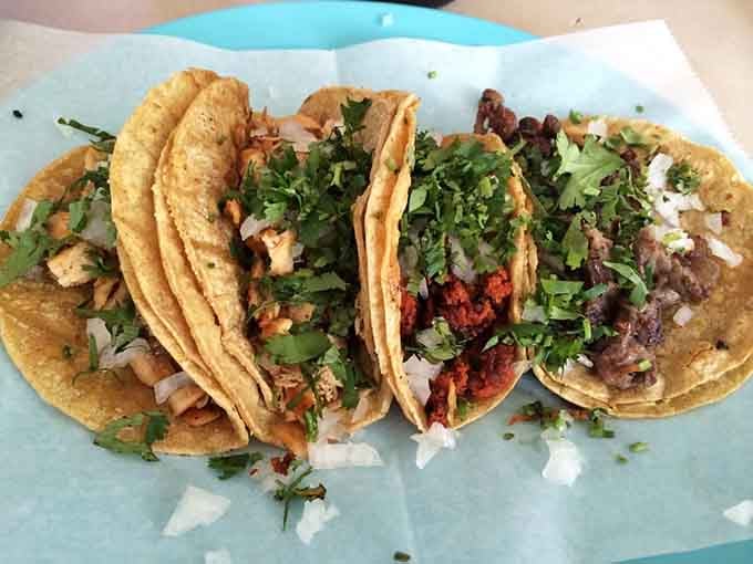 Three tacos lined up like the best decision you've made all week. Pollo, chorizo, and asada, ready to go.