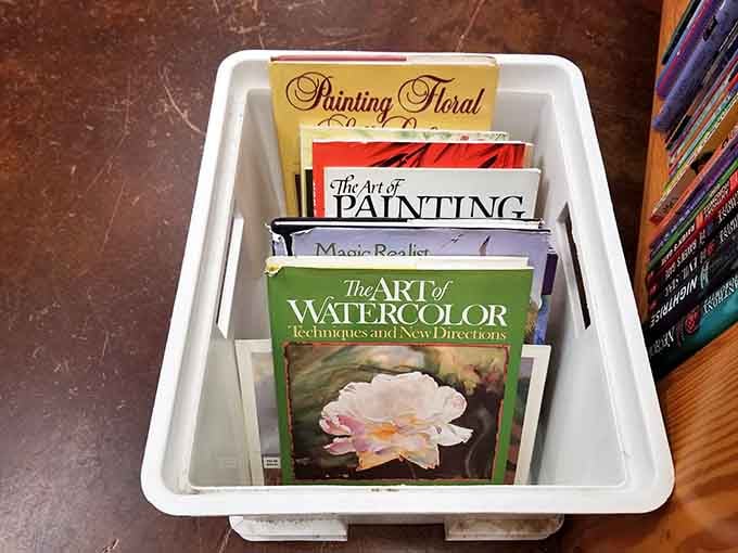 Tucked in a floor bin, watercolor guides and painting books wait patiently for the next artist to discover them.