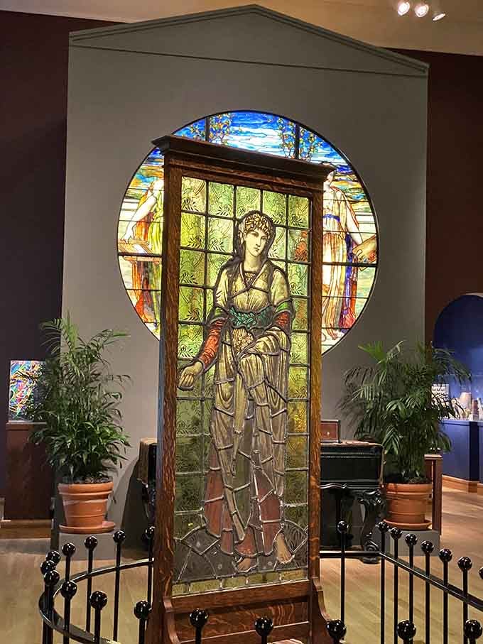 That floor-to-ceiling figural window framed in oak and set against a circular backdrop is Tiffany storytelling at its most theatrical and breathtaking.
