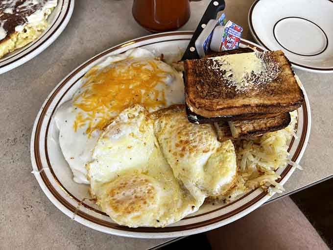 Eggs, hash browns, and buttered toast on one plate. Breakfast has never looked this confidently no-nonsense.